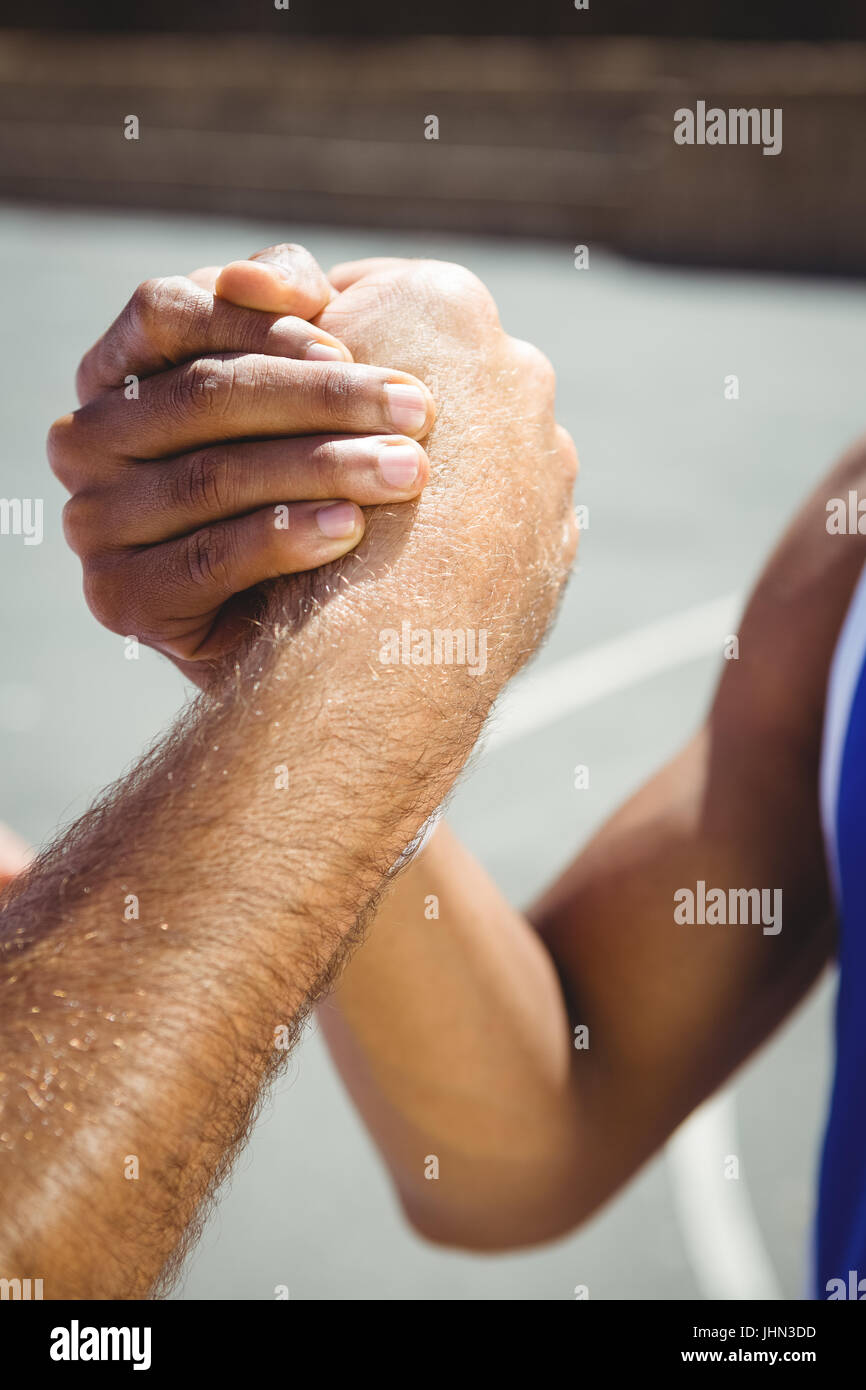 Cropped image of male basketball players holding hands while playing in ...