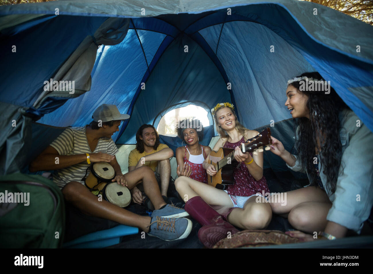 Happy young friends enjoying while sitting together in tent Stock Photo ...