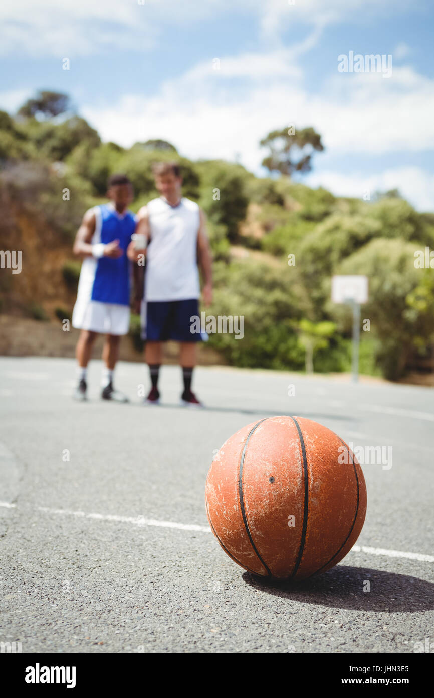 Basketball on ground with player standing in background at court Stock ...