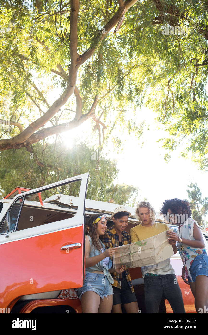 Low angle view of friends reading map by camper van at campsite Stock ...