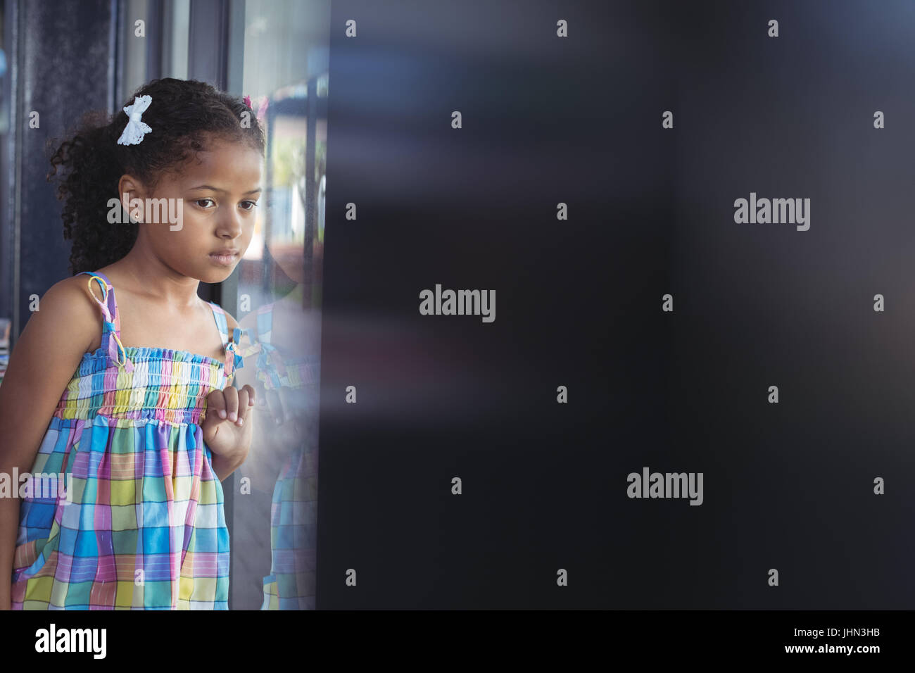 Thoughtful girl looking through window in school Stock Photo - Alamy