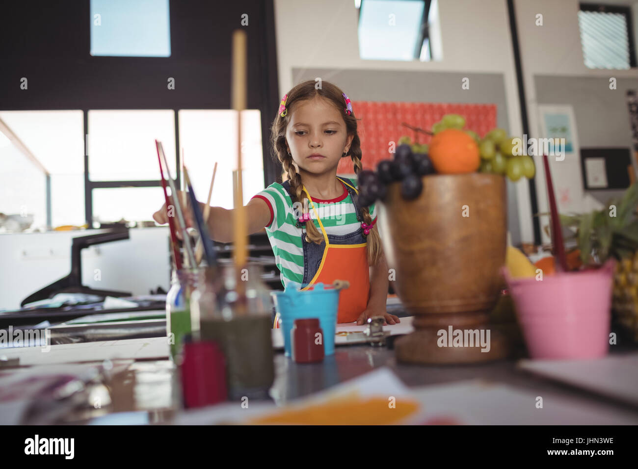 Girl holding paintbrush while painting in classroom at school Stock ...