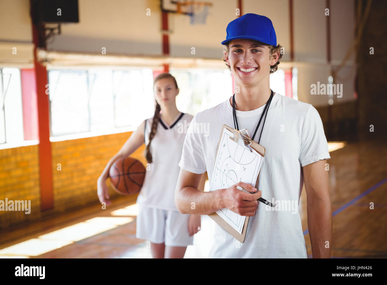 Portrait of male coach with basketball player standing in court Stock ...