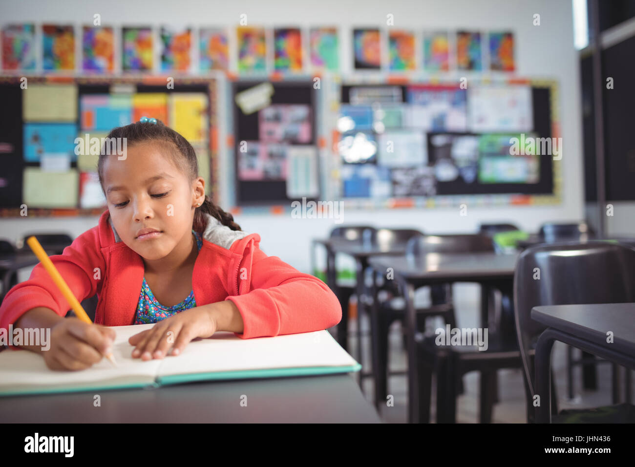 Girl studying while sitting at desk in classroom Stock Photo - Alamy