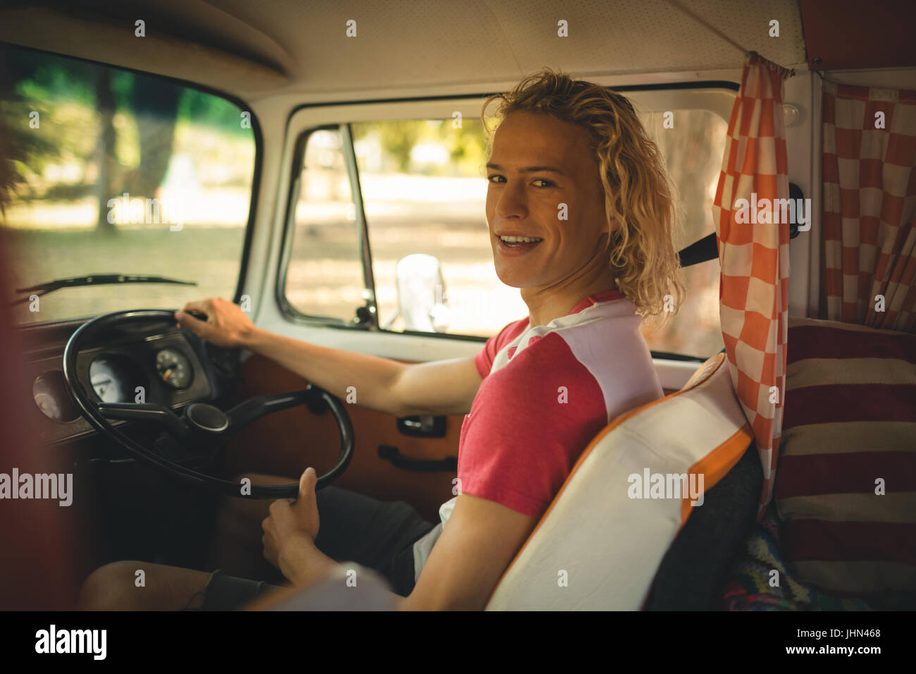 Portrait of smiling young man driving camper van Stock Photo - Alamy