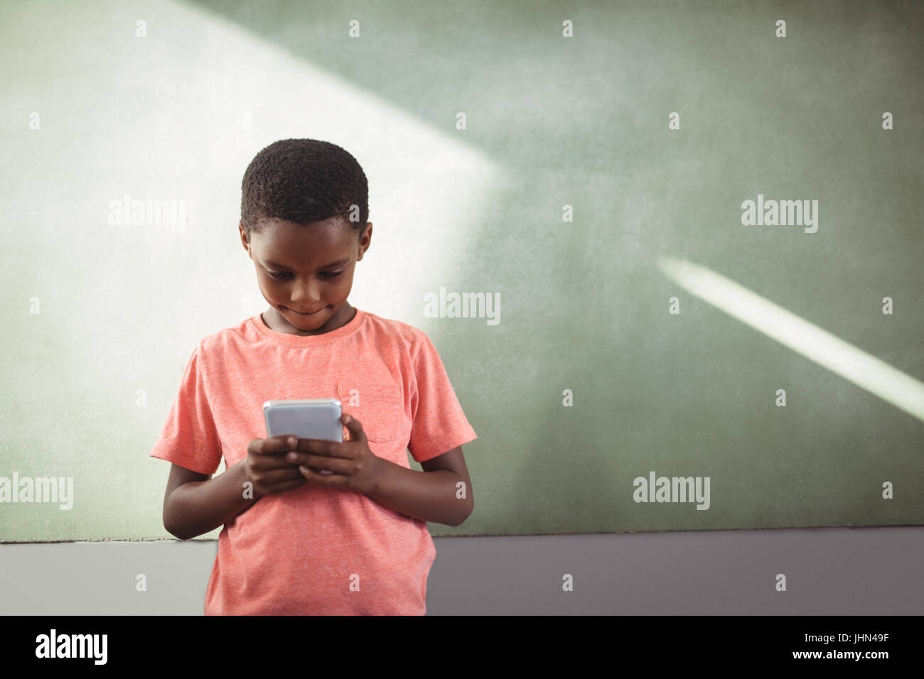 Boy using cellphone while standing against greenboard in school Stock ...