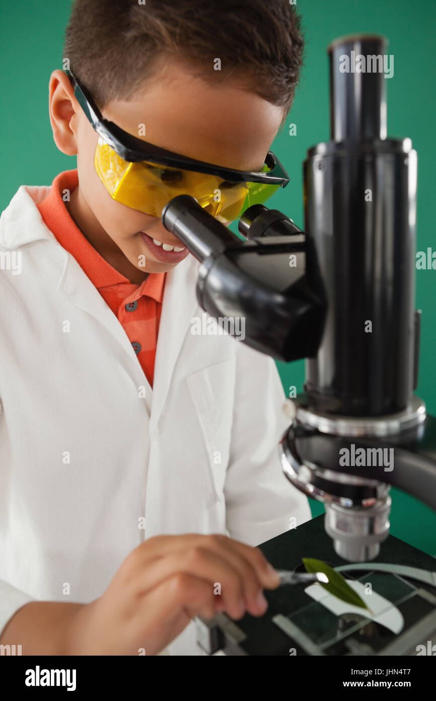 Schoolboy using microscope against green background Stock Photo - Alamy