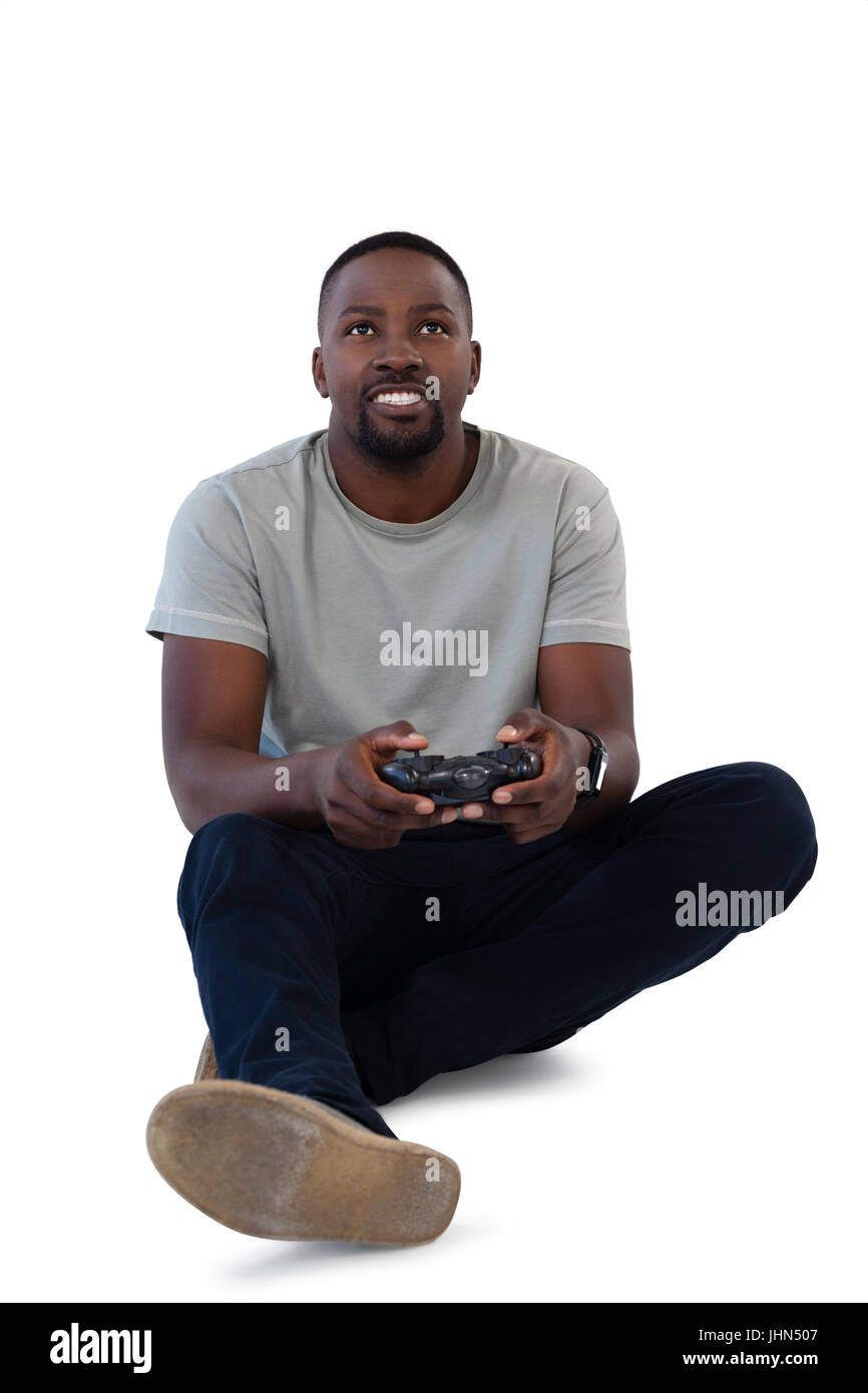 Smiling man playing video game against white background Stock Photo - Alamy
