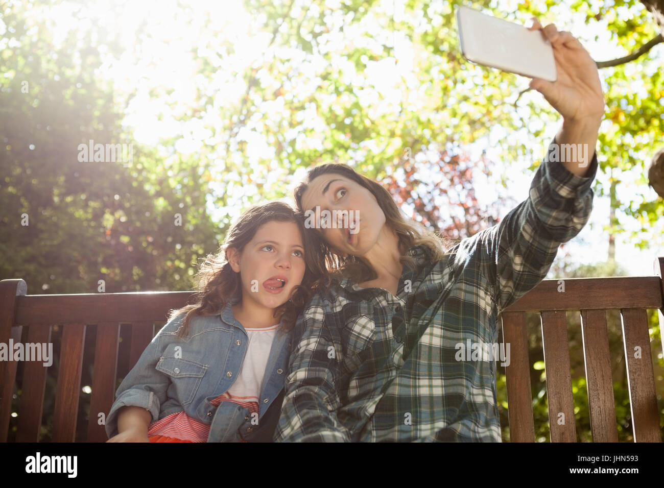Low angle view of woman taking selfie with daughter while making faces ...