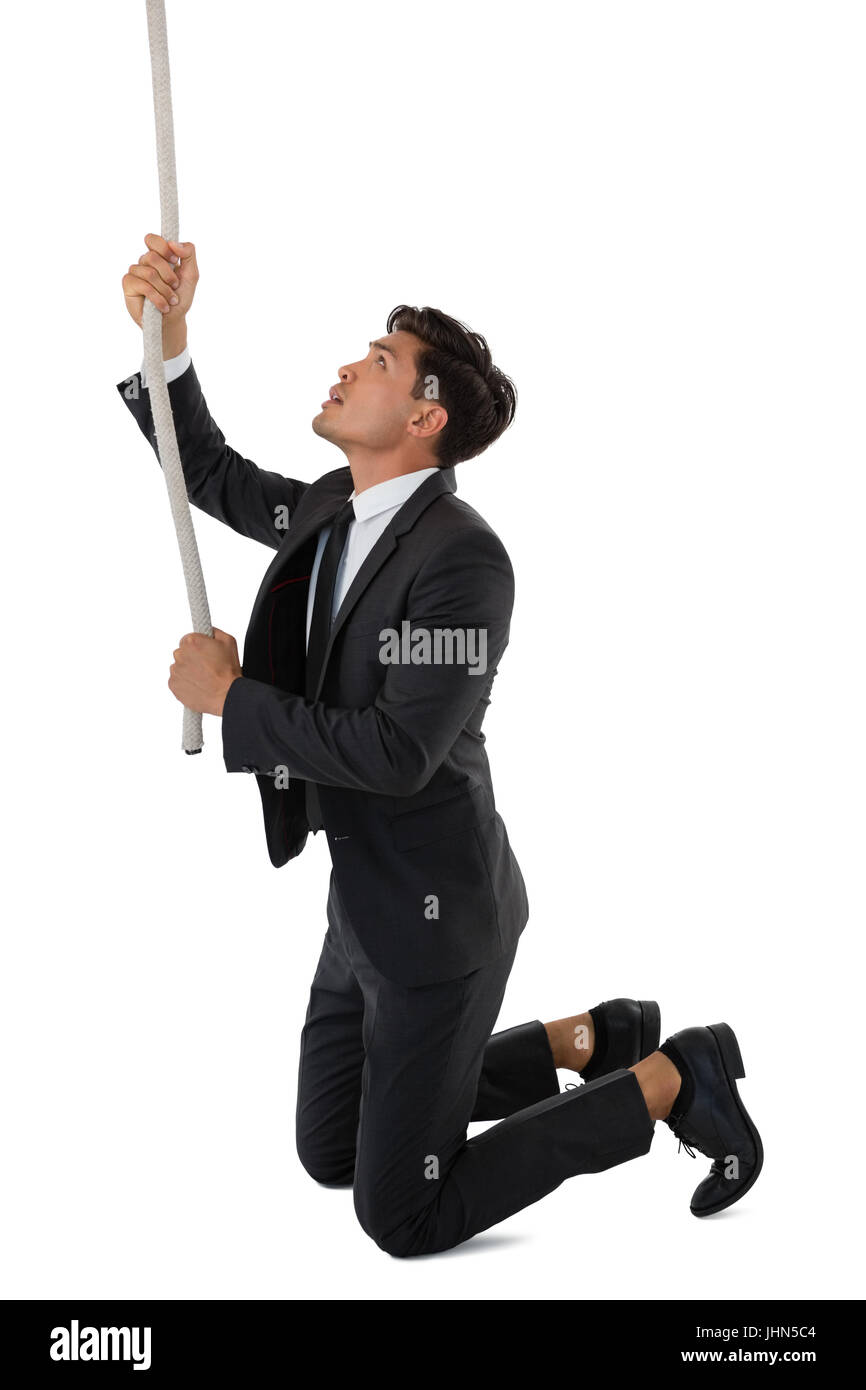 Side view of businessman pulling rope while kneeling against white ...