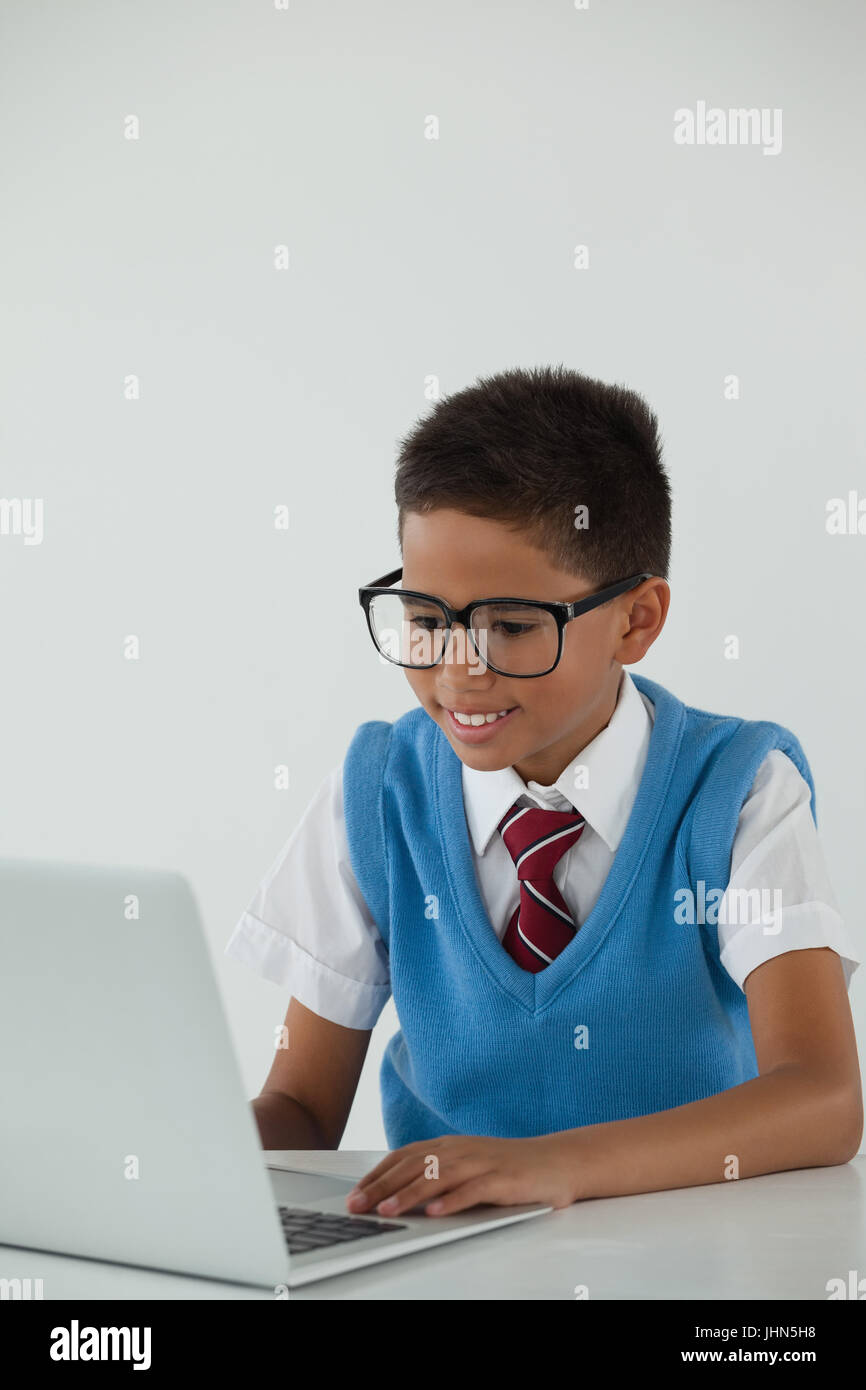 Schoolboy using laptop against white background Stock Photo - Alamy