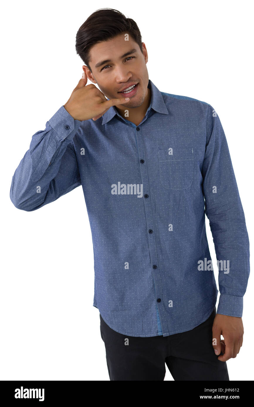 Portrait of businessman gesturing call hand sign against white ...