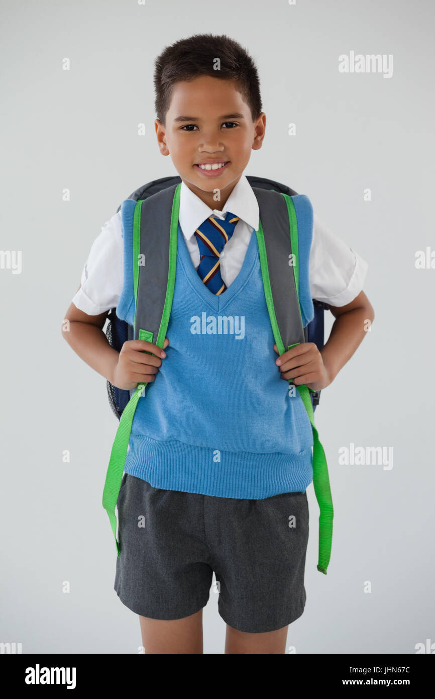 Portrait of schoolboy in school uniform with school bag on white ...