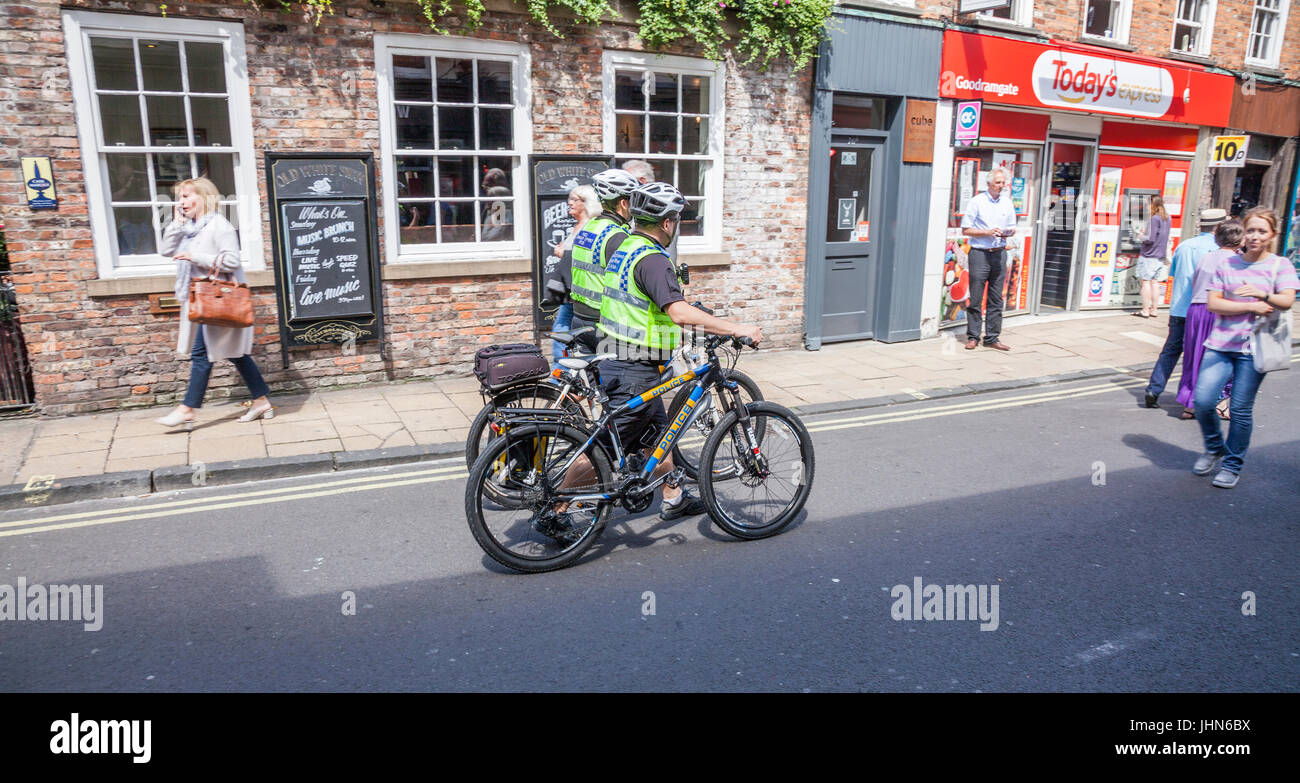 Two PCSO's walk their bikes through the busy streets of York,England,UK ...