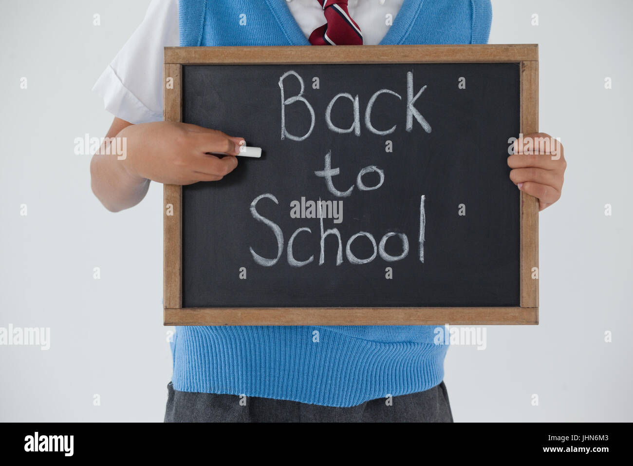 Mid section of schoolboy holding writing slate with text back to school ...