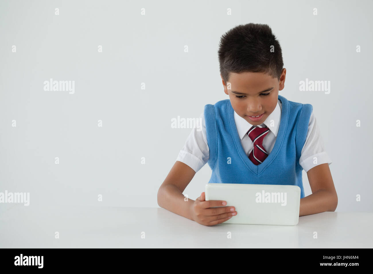 Schoolboy using digital tablet against white background Stock Photo - Alamy