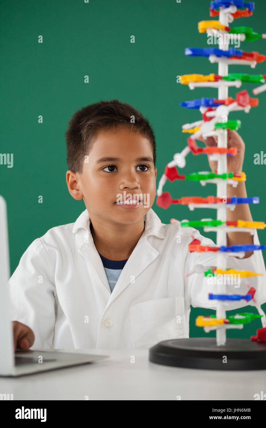 Smiling schoolboy experimenting molecule model in laboratory at school ...