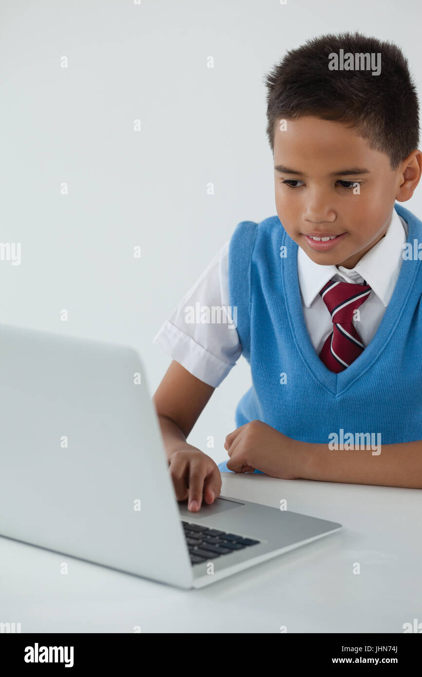 Schoolboy using laptop against white background Stock Photo - Alamy