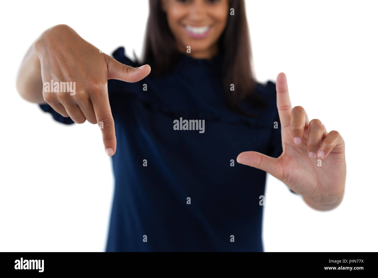 Smiling female executive forming a finger frame against white ...