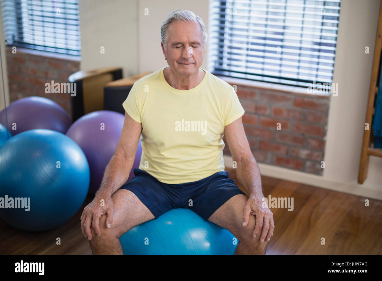 High angle view of senior male patient sitting on exercise ball with ...