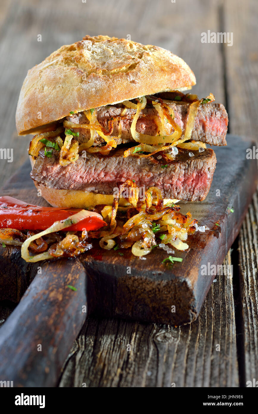 Big meat sandwich: Grilled beef fillet steak with fried onion rings on ...