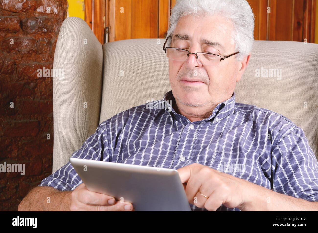 Portrait of an old man using digital tablet and sitting on couch ...