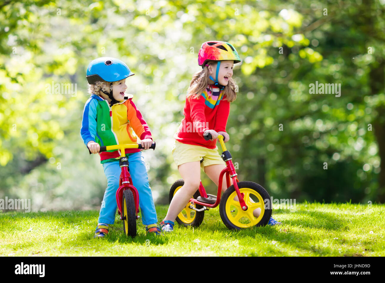 Children riding balance bike. Kids on bicycle in sunny park. Little ...