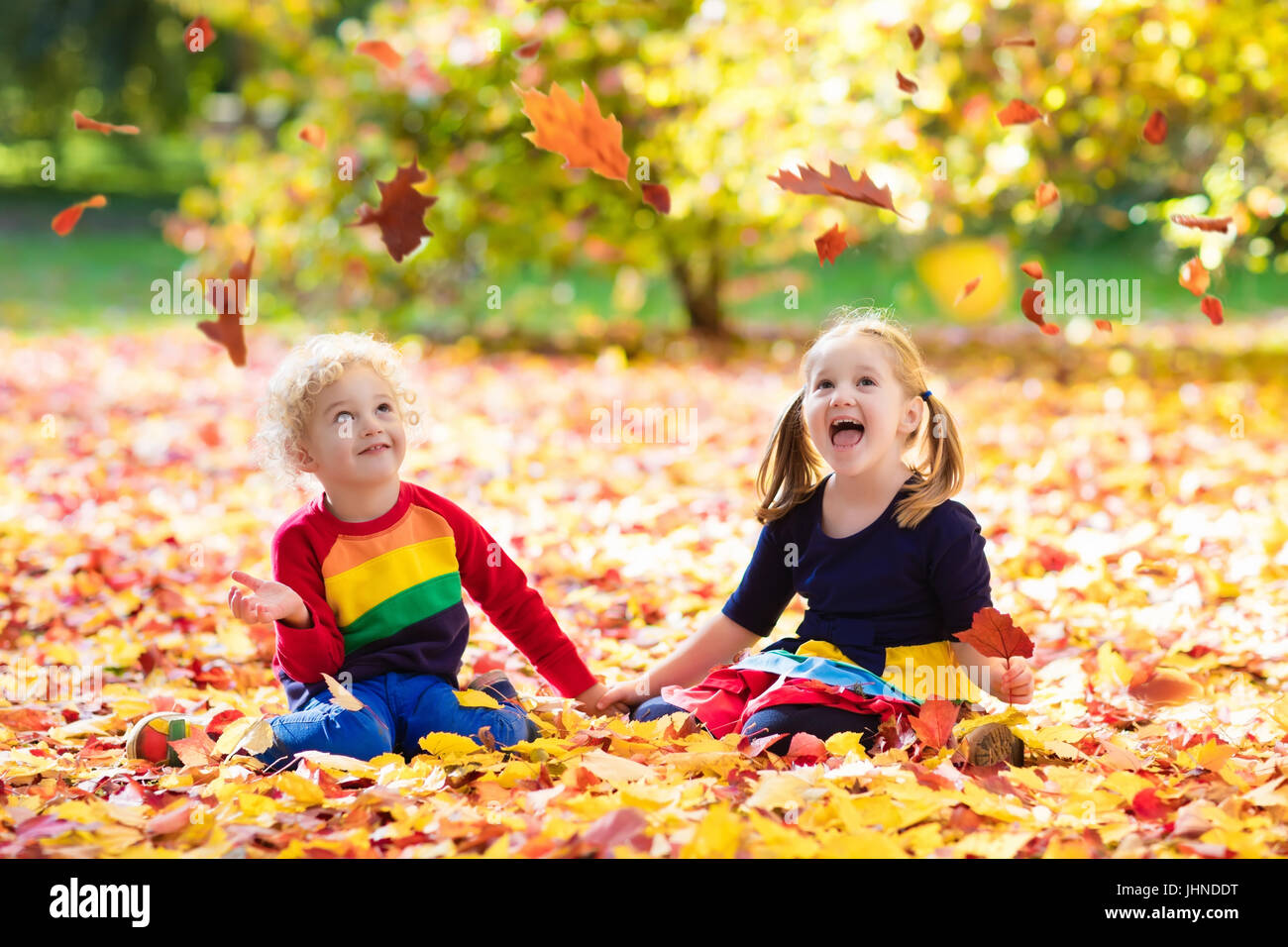 Kids play in autumn park. Children throwing yellow maple leaves. Boy ...