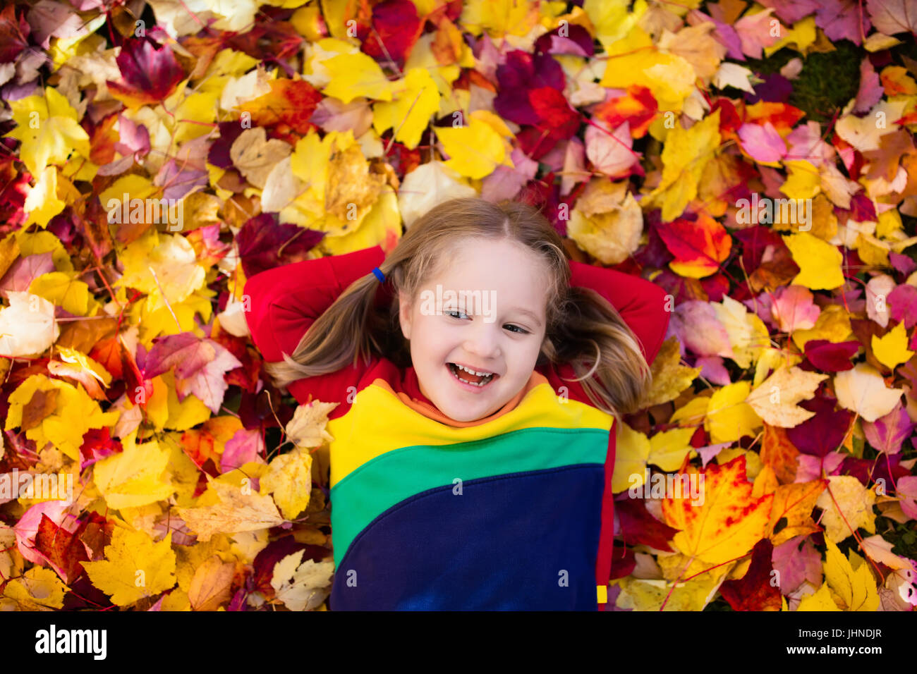 Kids play in autumn park. Children throwing yellow and red leaves ...