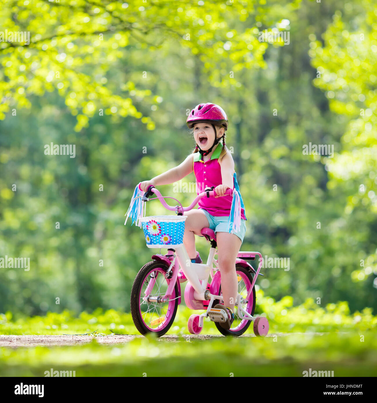 Child riding bike. Kid on bicycle in sunny park. Little girl enjoying ...