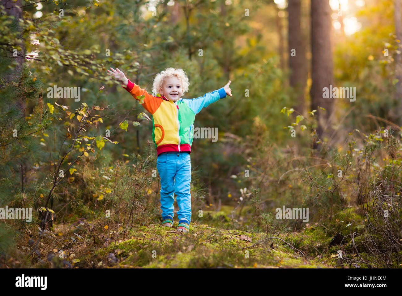 Kids play in autumn park. Children throwing yellow and red leaves ...