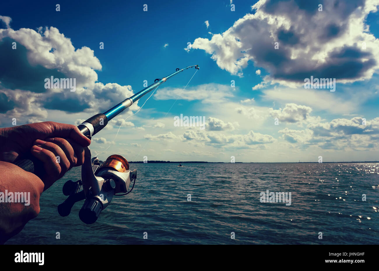 hand holding a fishing rod with reel. Focus on Fishing Reels. Toned ...