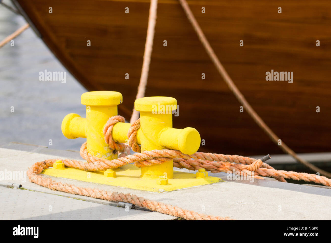 Rope and yellow mooring bollard in port, closeup and detail of seaport ...