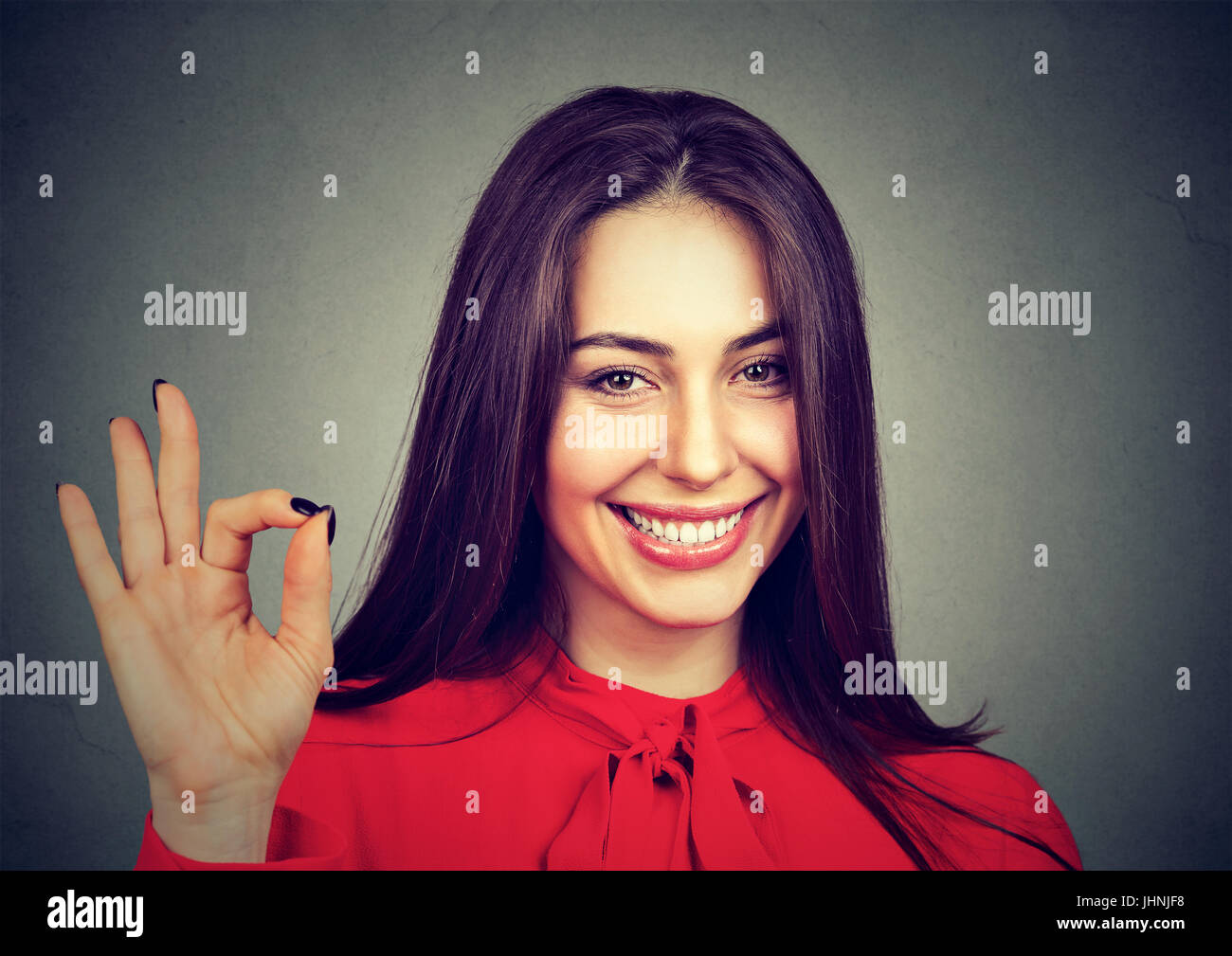 Laughing woman showing ok sign isolated on gray background Stock Photo ...