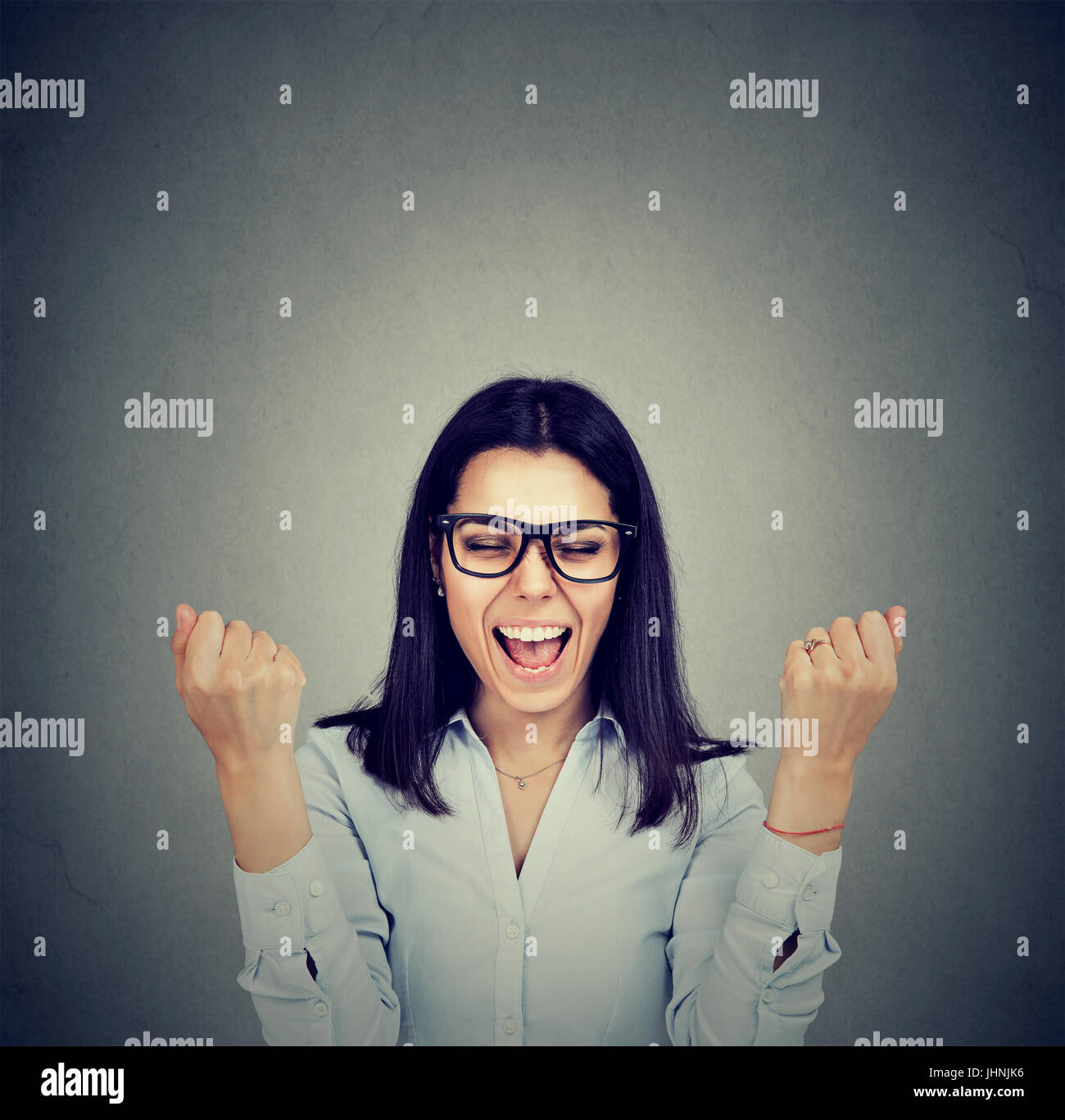 happy woman exults pumping fists celebrates success on gray wall ...