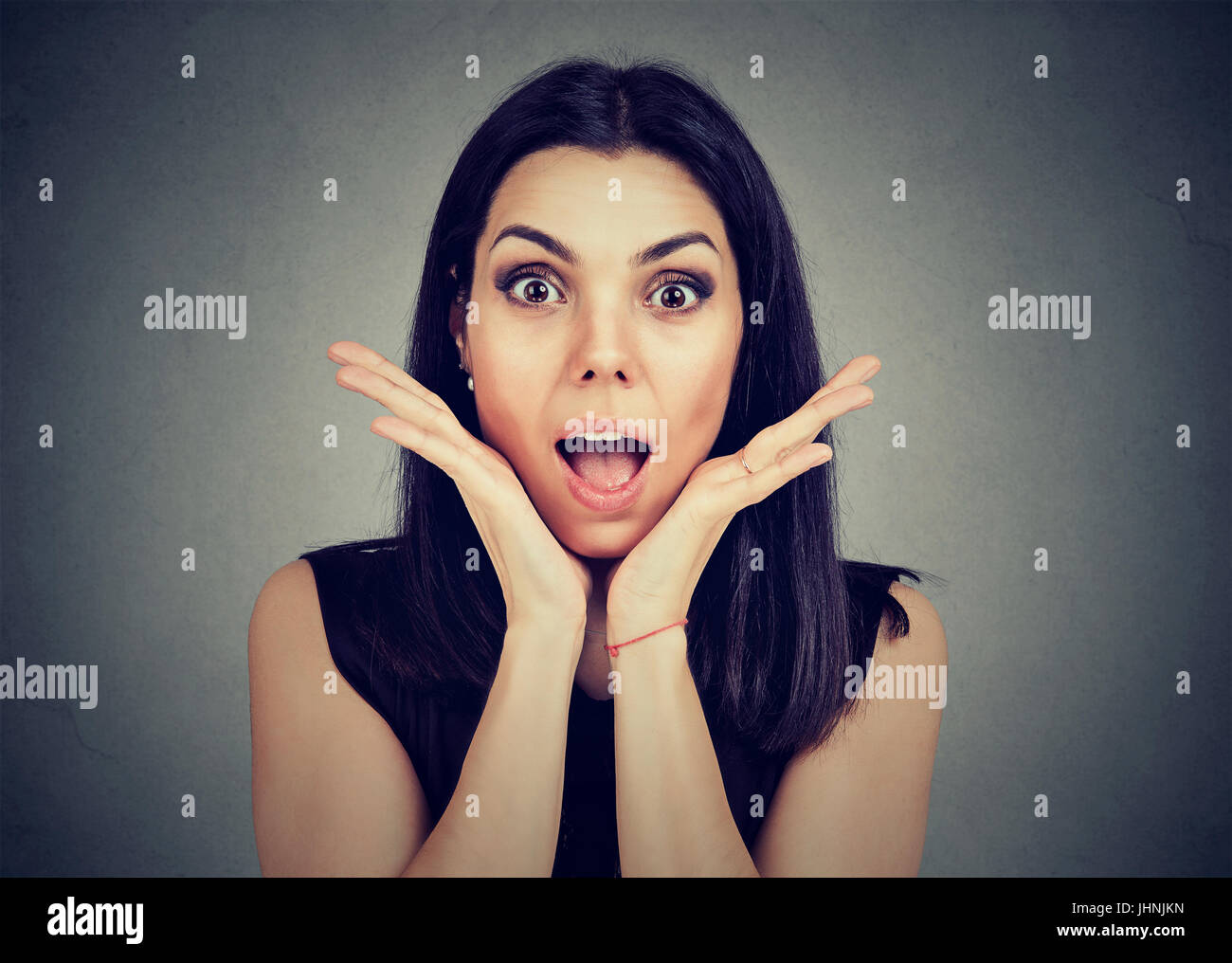 Surprised young woman shouting over gray background Stock Photo - Alamy