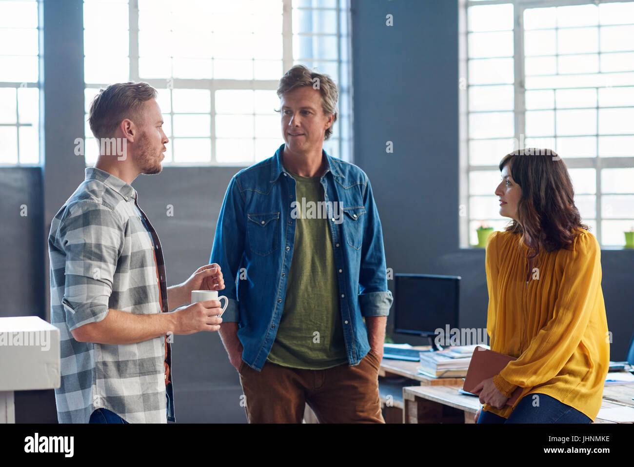Three collegues standing in a modern office talking together Stock ...