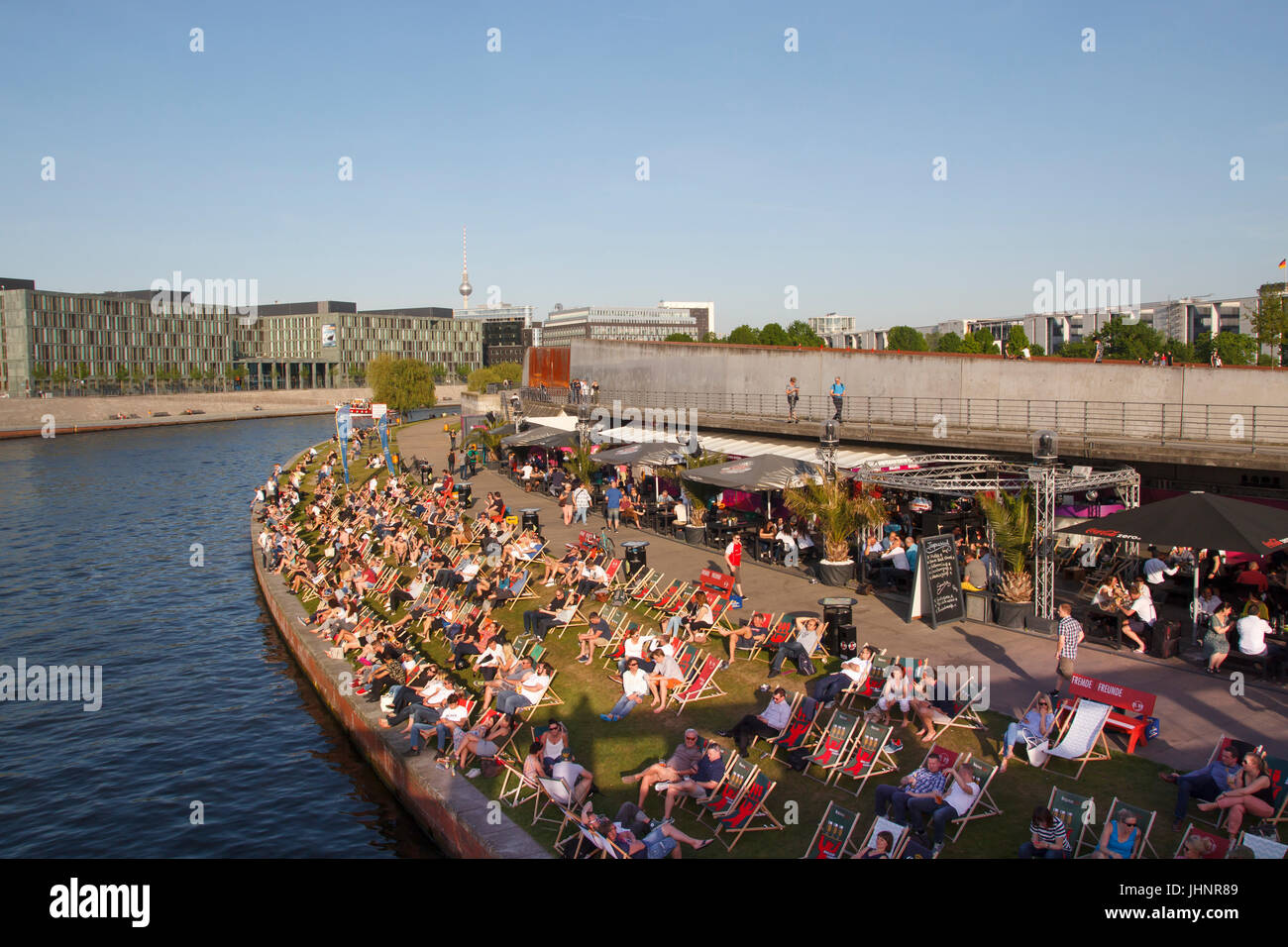 People sitting in Spree riverside, having fun and enjoying some drinks ...