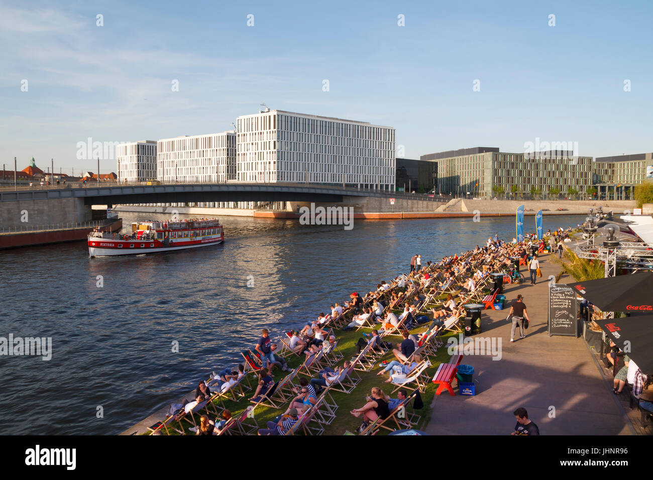 People sitting in Spree riverside, having fun and enjoying some drinks ...