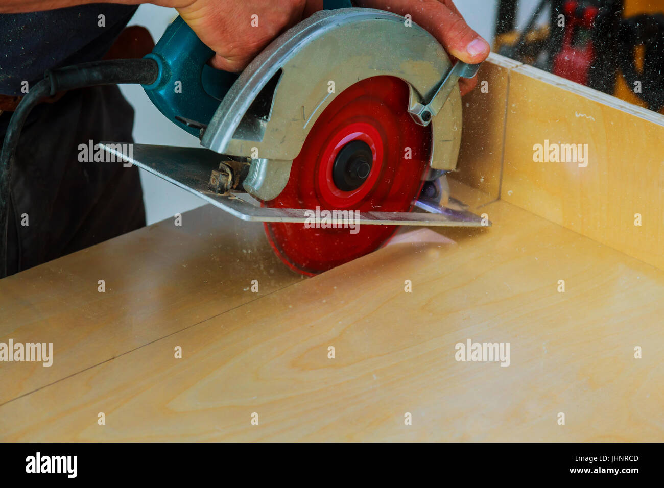 carpenter uses a circular saw to cut wood on the work area Circular saw ...
