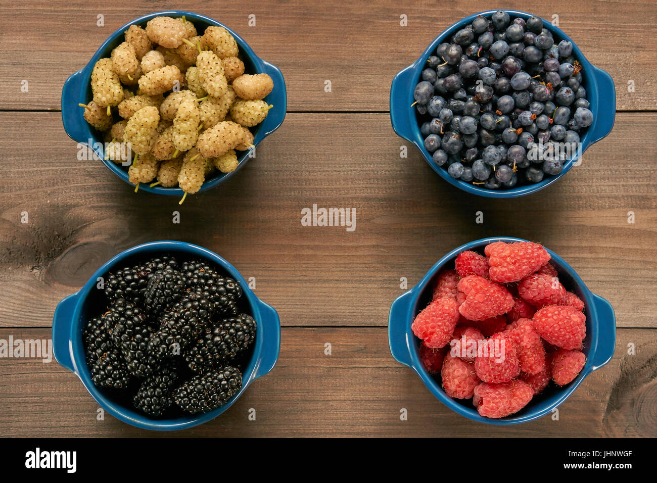 four ceramic bowls with berries. raspberry, mulberry, blueberry ...
