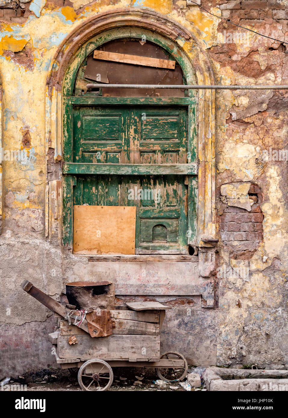 Front view of a wooden cart parked under a grungy window in a derelict ...