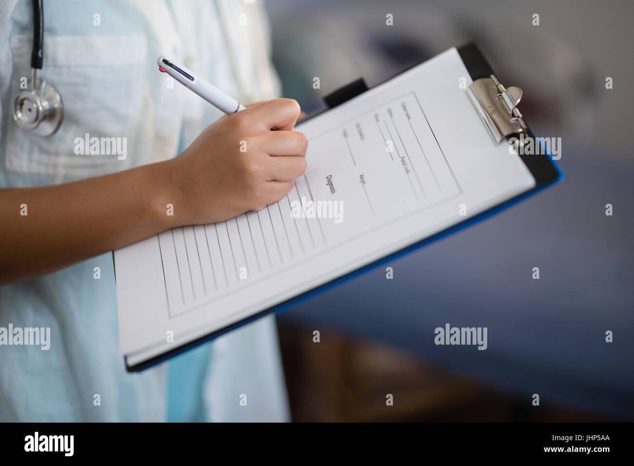 Midsection of female doctor writing on clipboard at hospital ward Stock ...