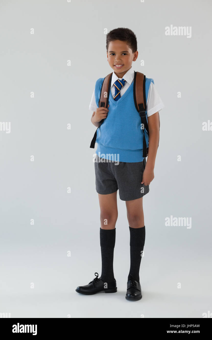 Portrait of schoolboy in school uniform with school bag on white ...