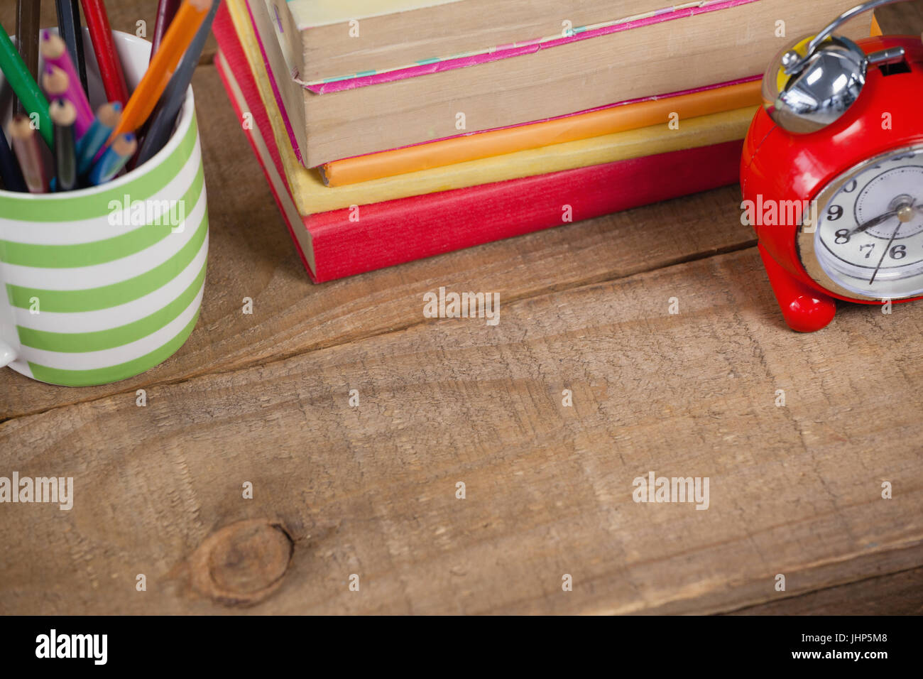 Stack of books, alarm clock and pen holder on wooden background Stock ...