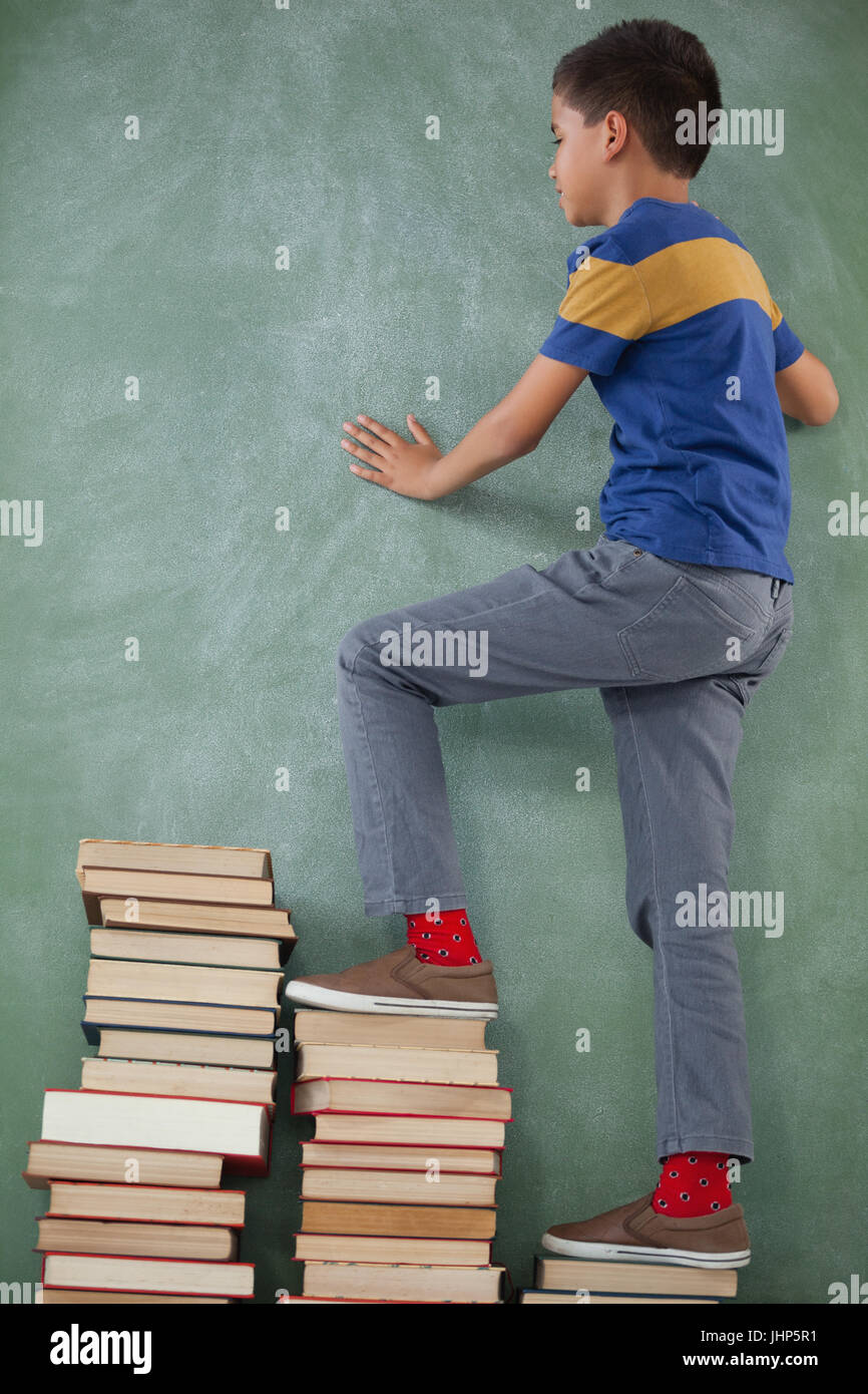 Boy climbing stack of books hi-res stock photography and images - Alamy