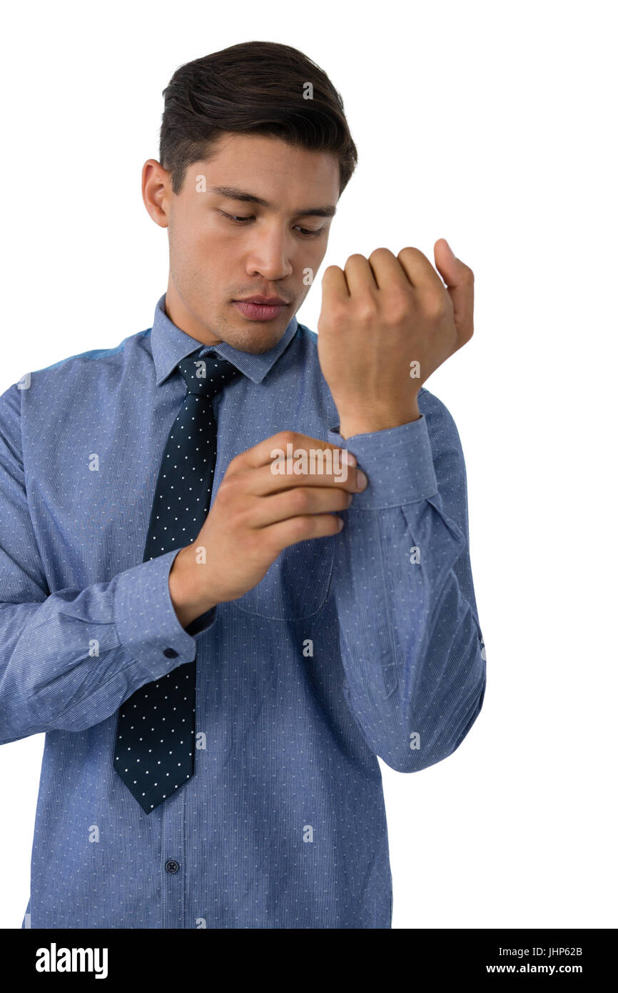Businessman buttoning cuff while standing against white background ...