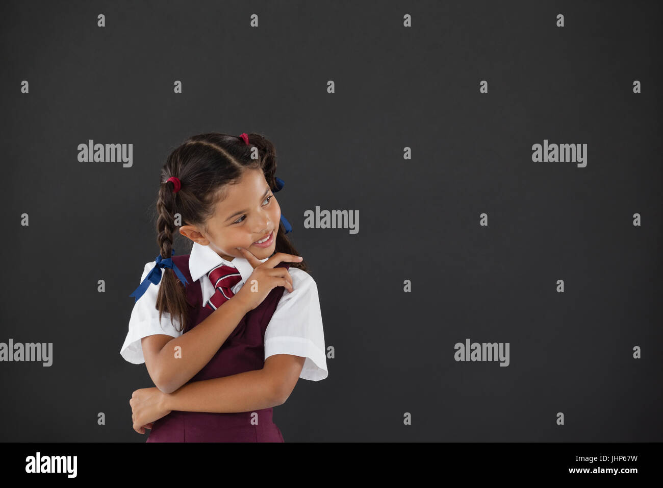 Thoughtful schoolgirl standing against blackboard in classroom Stock ...