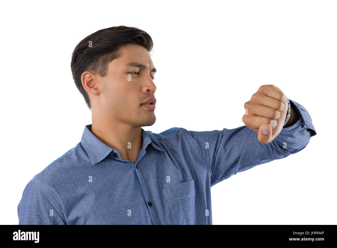 Businessman looking at wristwatch while standing against white ...