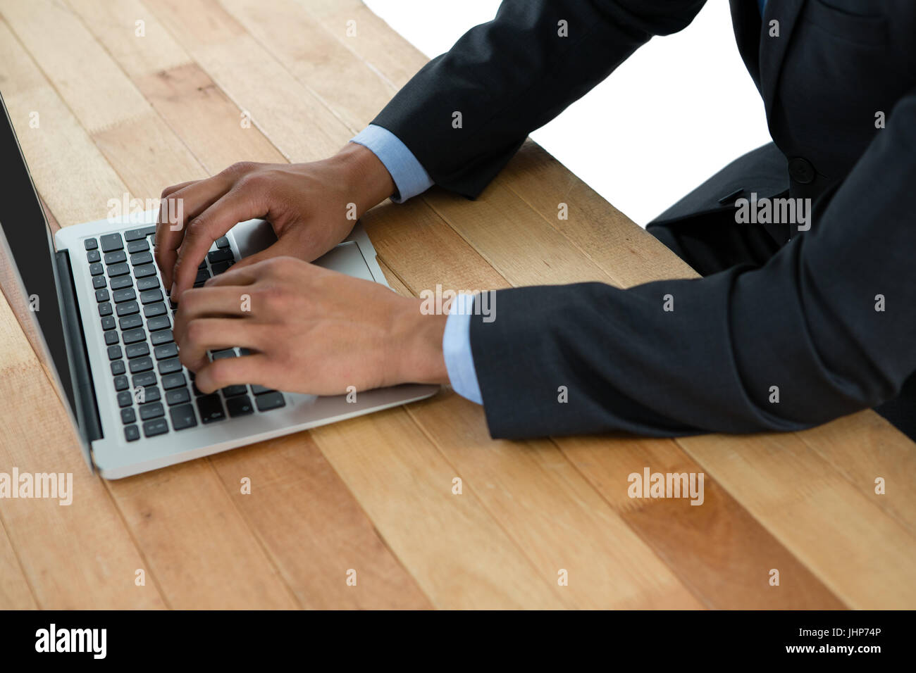 Mid section of businessman using laptop at table against white ...